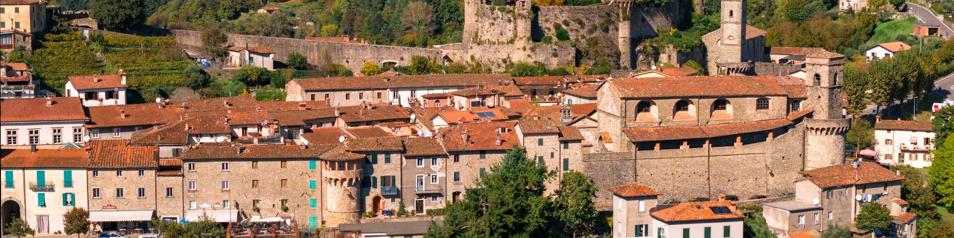 Uma cidade histórica com arquitetura medieval, incluindo uma torre imponente e muralhas fortificadas.