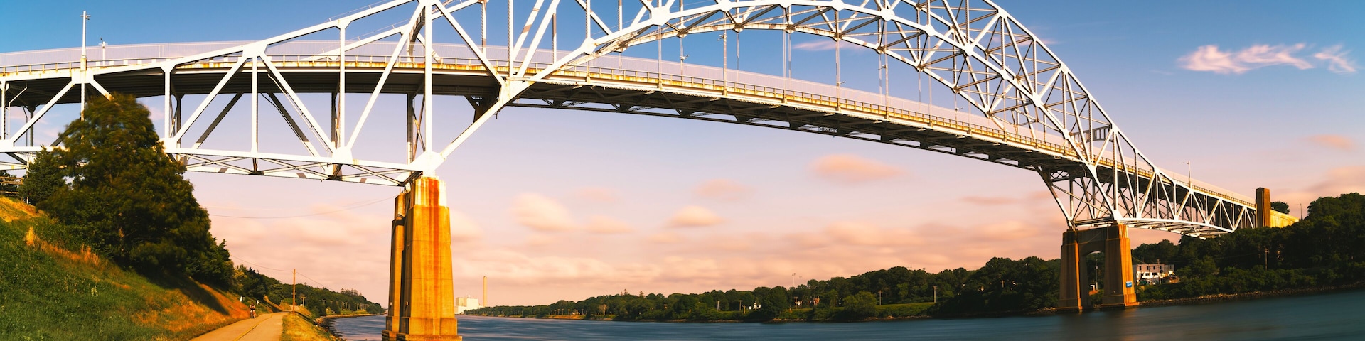 Uma extensa ponte de aço atravessa um rio sob um céu límpido.