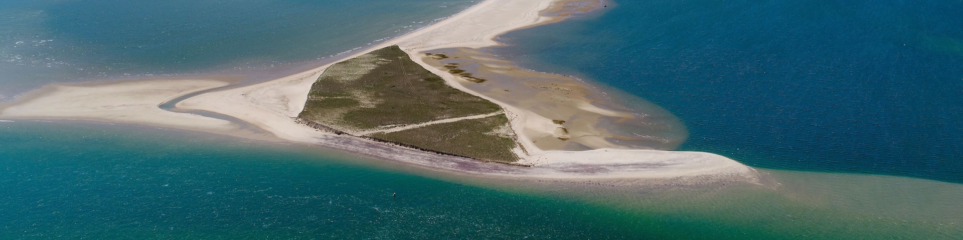Paisagem costeira com uma península arenosa proeminente, rodeada por águas azul-turquesa.
