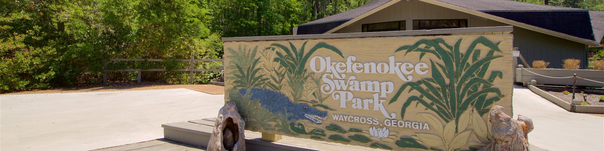 Placa de madeira para o Okefenokee Swamp Park com ilustração de um pântano e um edifício ao fundo.