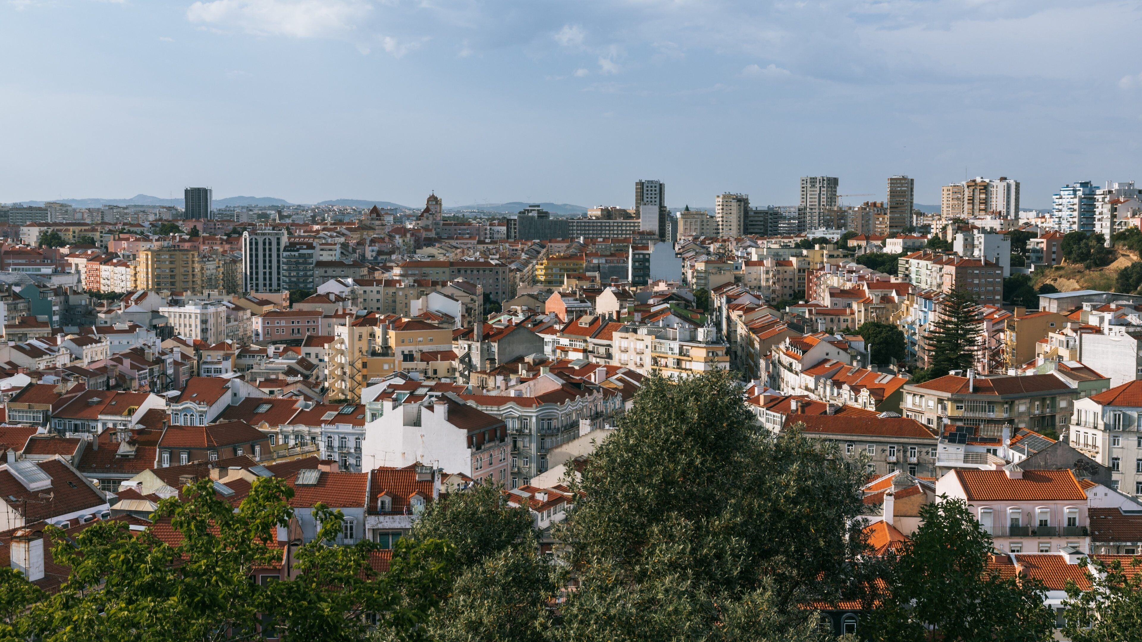 Uma área urbana densamente povoada, com uma mistura de arquitetura histórica e moderna, incluindo uma torre do relógio imponente e vários edifícios altos.