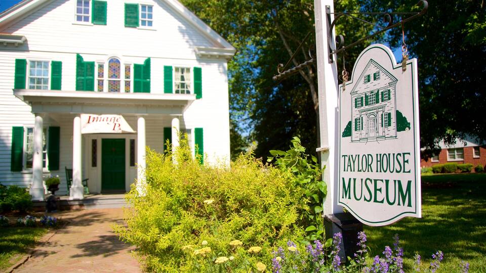 Um edifício branco com persianas verdes, identificado como o Museu Taylor House.
