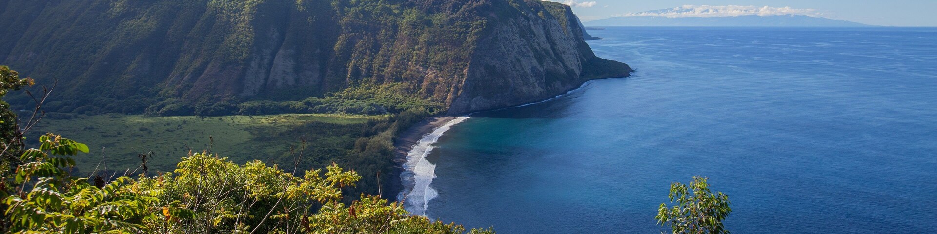 Paisagem costeira com um penhasco íngreme, uma praia e vista do oceano.