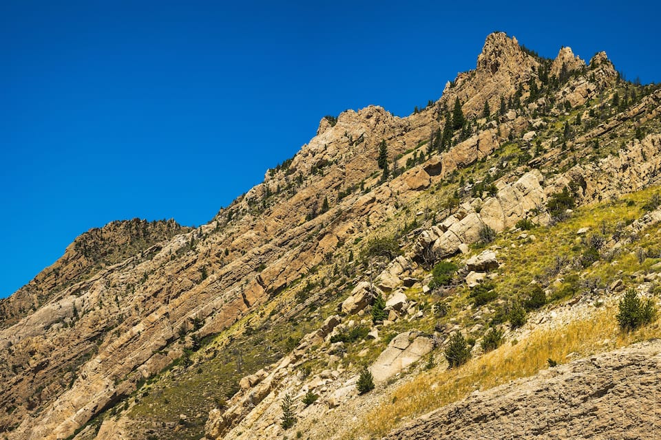 Montanha acidentada com terreno rochoso e vegetação escassa.