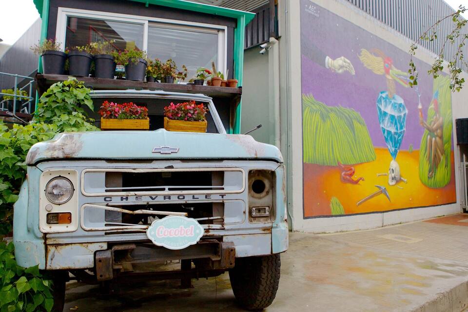 Uma caminhonete Chevrolet antiga estacionada em frente a um edifício com um mural colorido.