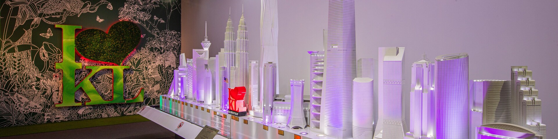 Exposição de maquetes iluminadas de arranha-céus em um museu.