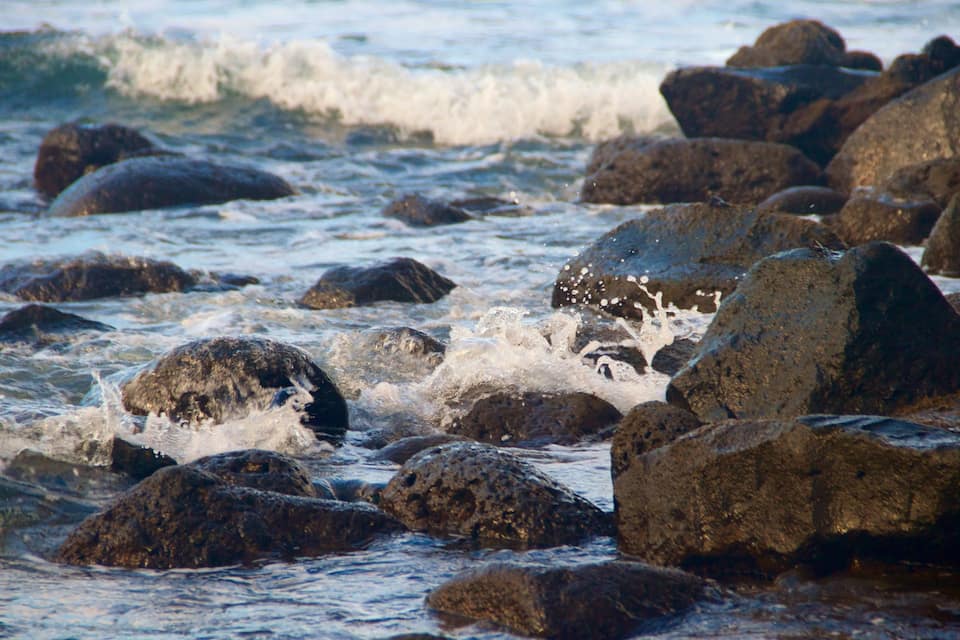 Uma costa rochosa com ondas quebrando nas pedras.