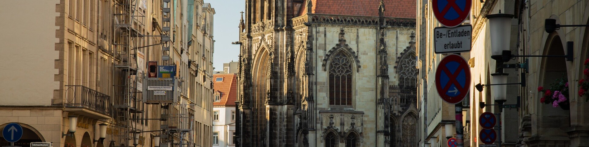 Uma igreja histórica com arquitetura elaborada, rua de paralelepípedos e cafés ao ar livre.