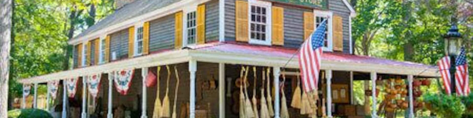 Uma loja de produtos rurais com varanda, bandeiras americanas e um letreiro que diz 'Country Store'.