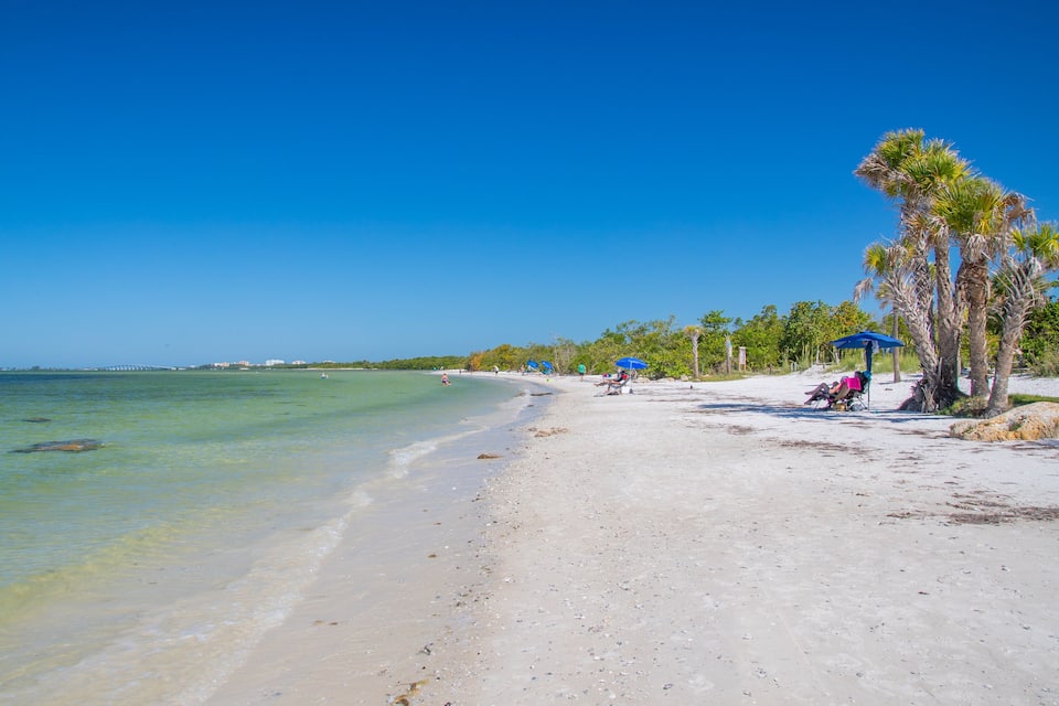 Uma praia com águas turquesa cristalinas, areia branca e palmeiras.