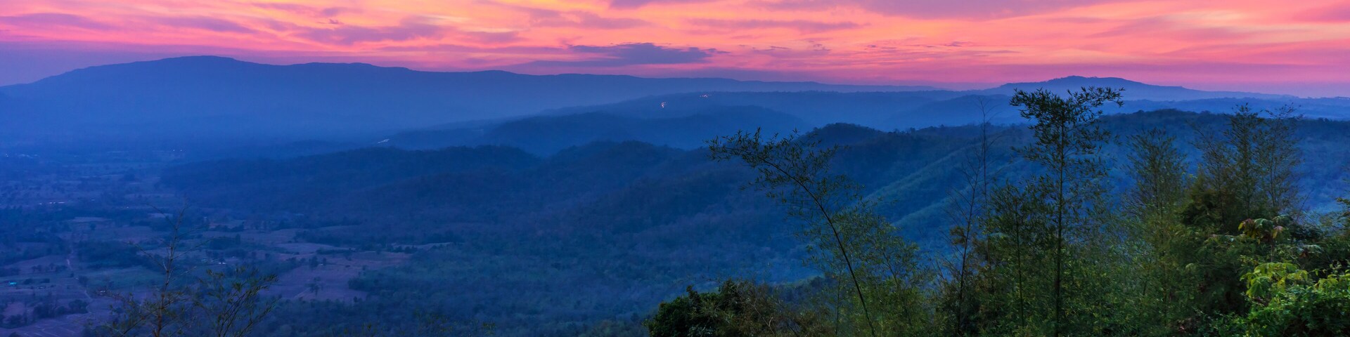 Paisagem montanhosa com um céu vibrante ao pôr do sol.