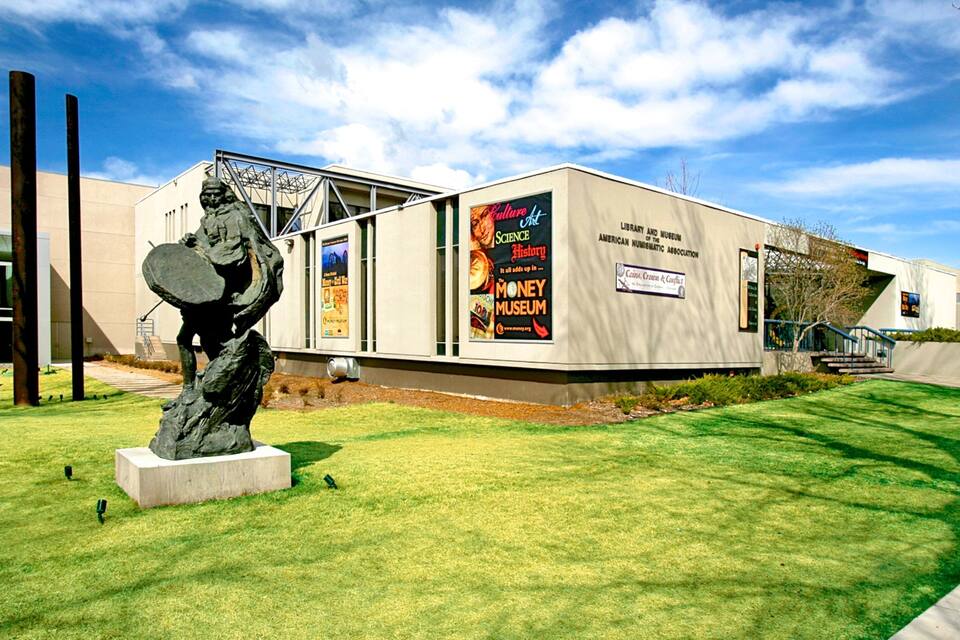 Um edifício de museu com uma escultura em frente.