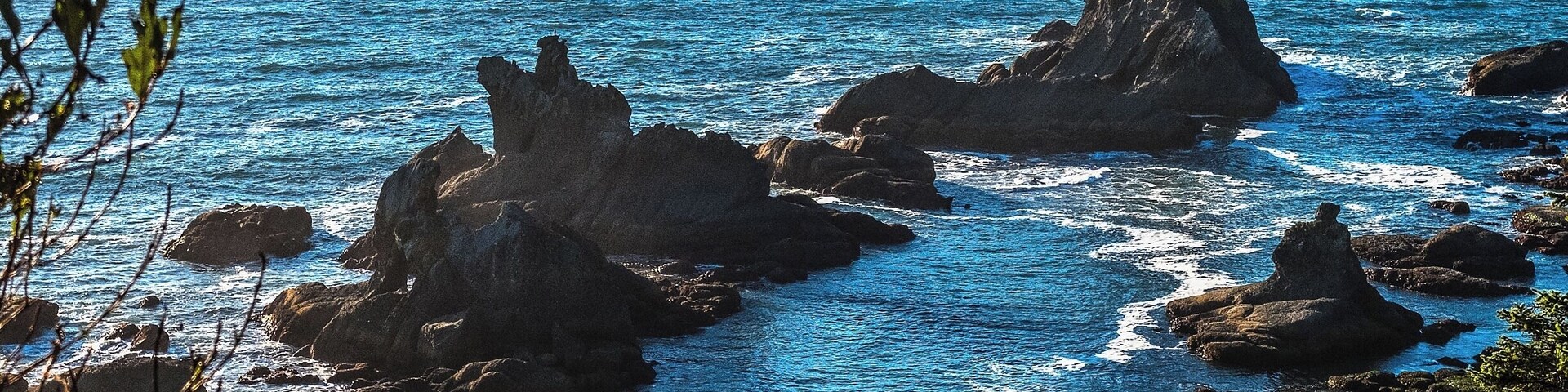 Litoral rochoso com formações rochosas imponentes e águas azul-claras.