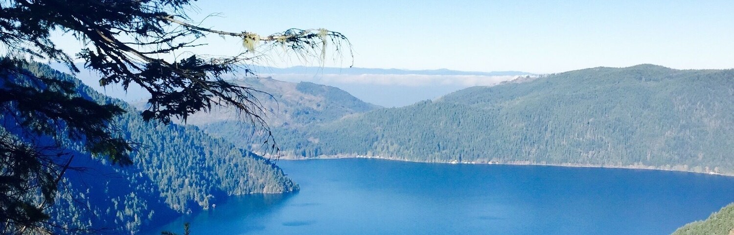 Um lago azul límpido rodeado por colinas arborizadas.