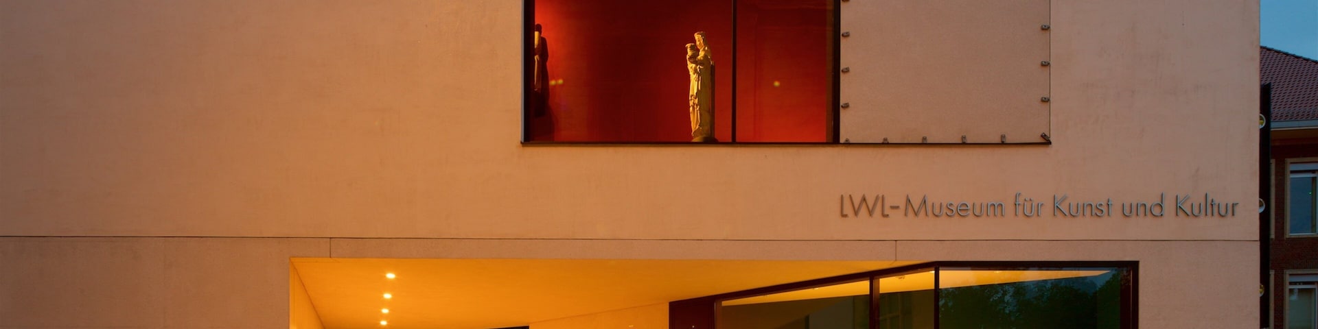 Um edifício moderno com fachada de vidro que exibe esculturas.