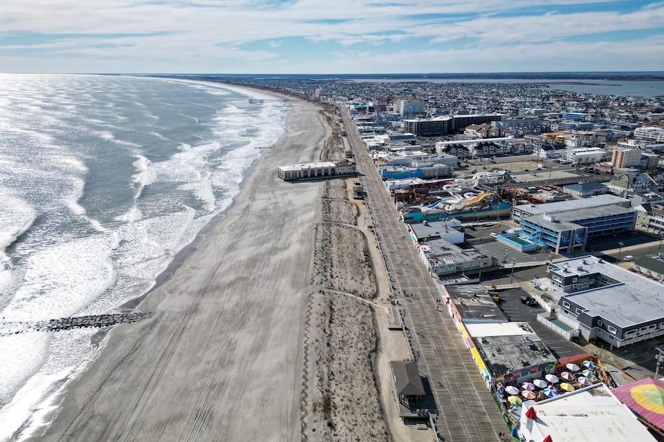 Uma cidade costeira com praia, calçadão e edifícios industriais.