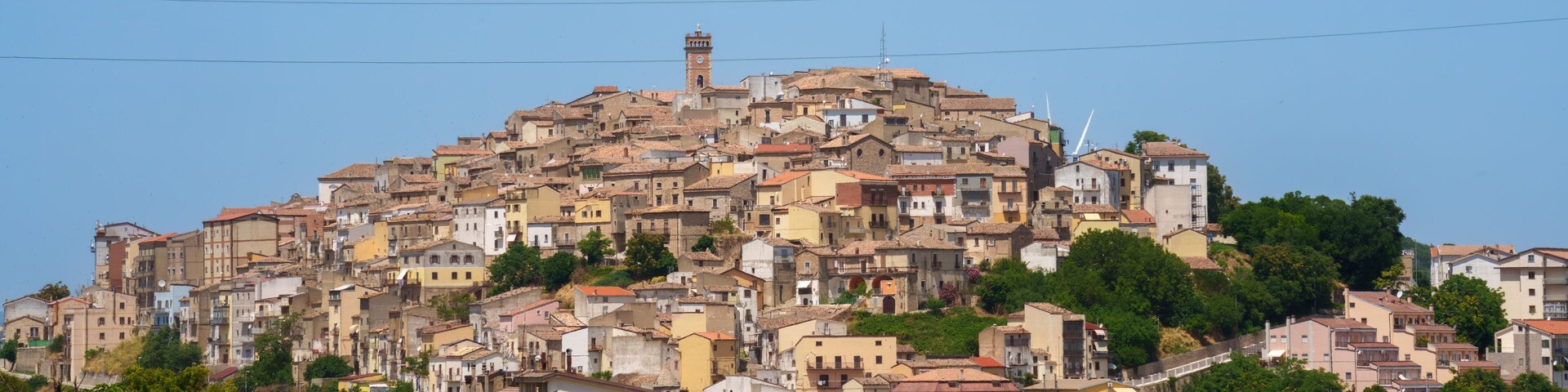 Uma cidade nas encostas de uma colina, com construções históricas e uma torre imponente.