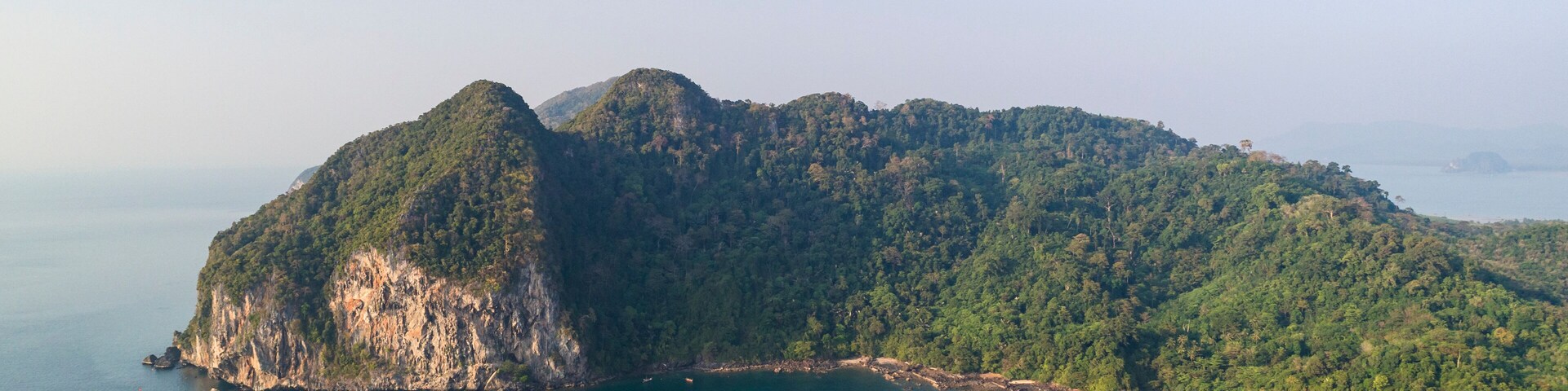 Uma ilha montanhosa coberta por florestas verdejantes e um mar tranquilo.