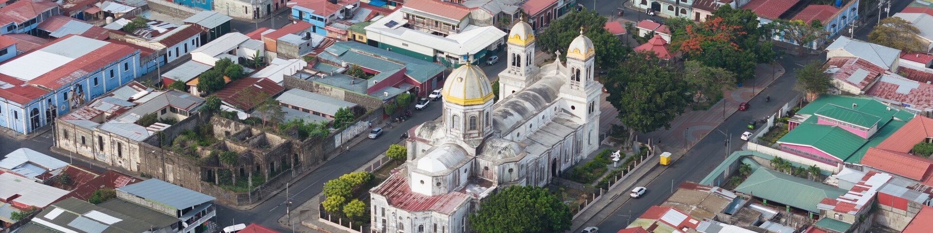 Vista aérea de uma área urbana densamente povoada, com edifícios coloridos, uma igreja imponente com cúpula dourada e uma grade de ruas.