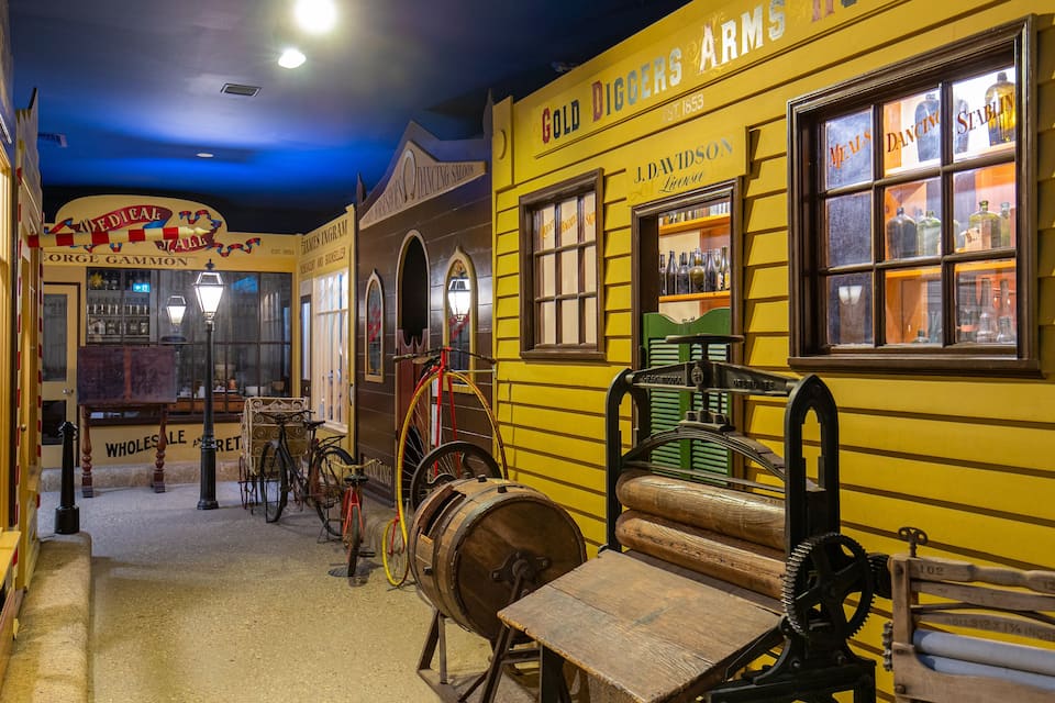 Interior de restaurante com tema vintage, paredes amarelas, mobiliário de madeira e decoração histórica.