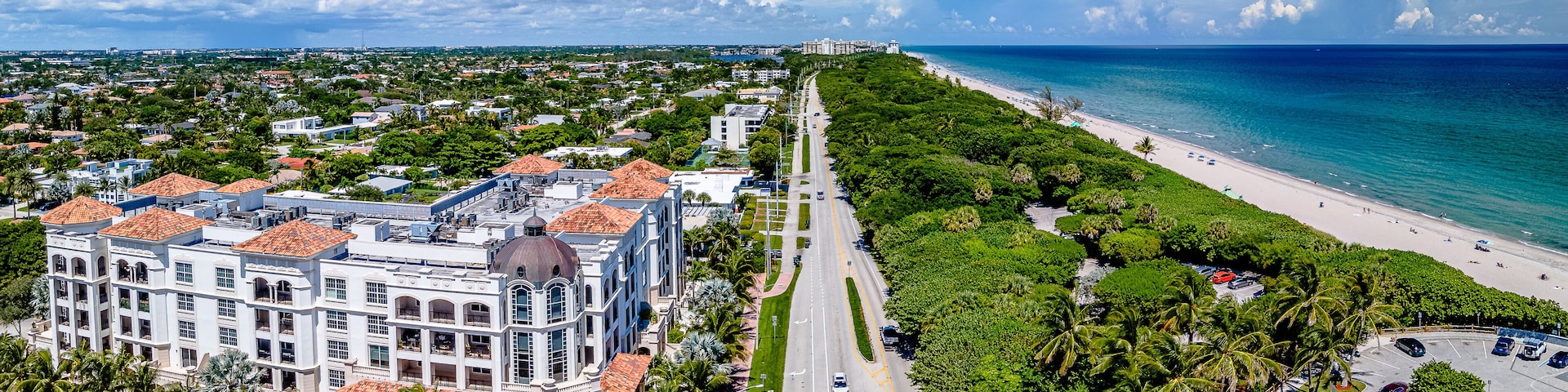 Paisagem costeira urbana com um hotel em destaque, uma praia e um céu azul límpido.