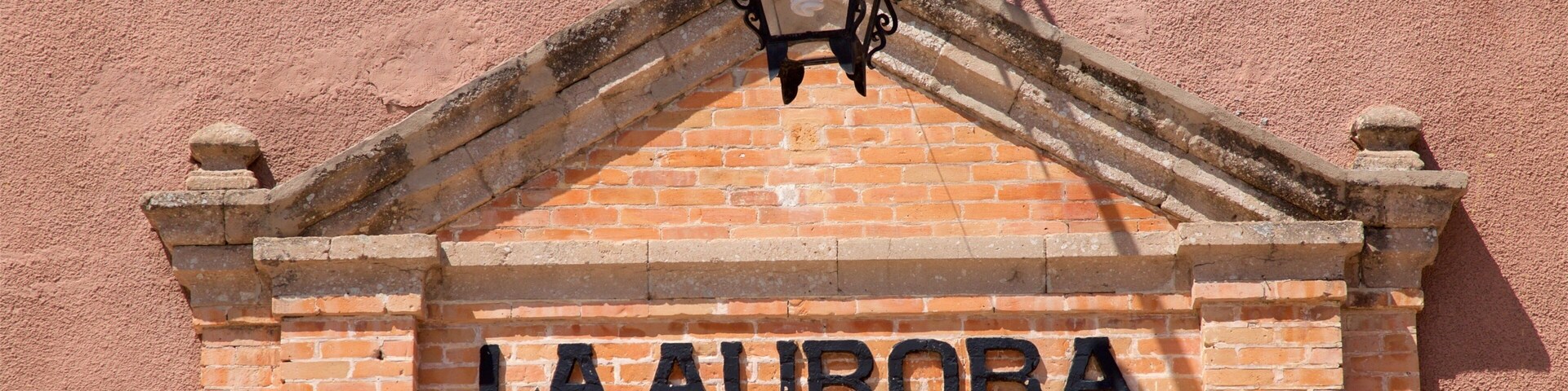 Um edifício de tijolos com a inscrição "LA AURORA" em sua fachada.