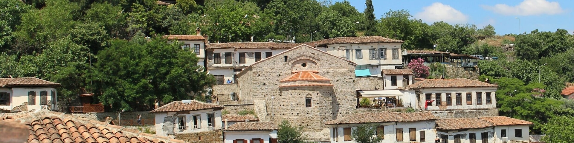 Uma aldeia na encosta com telhados de barro, edifícios de pedra e vegetação exuberante.