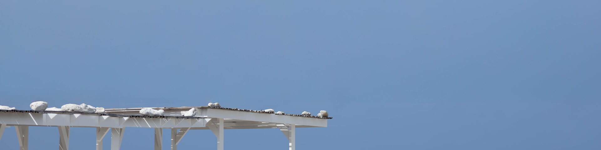 Um gazebo branco com vista desimpedida do oceano e céu azul.