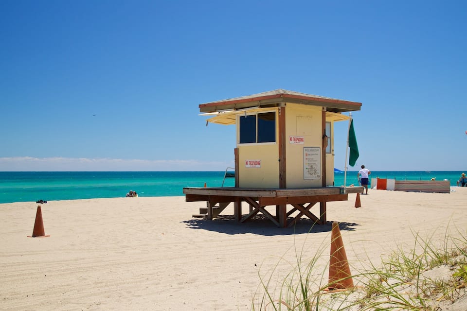 Uma torre de salva-vidas numa praia arenosa com águas turquesa cristalinas.