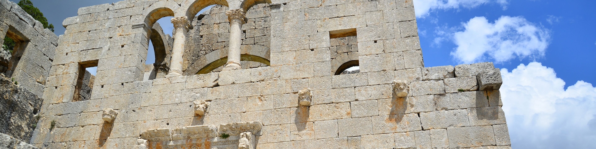 Ruínas antigas de pedra com arcadas e colunas.