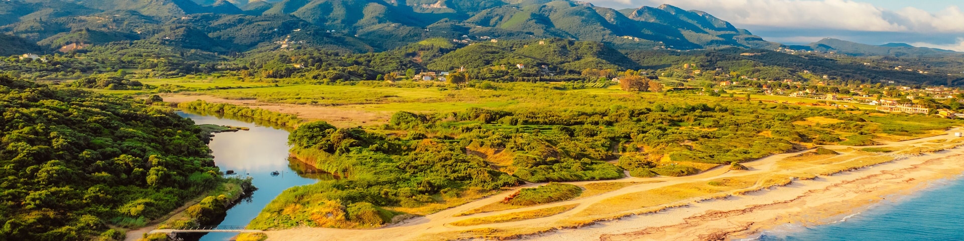 Paisagem costeira com rio, praia e montanhas.
