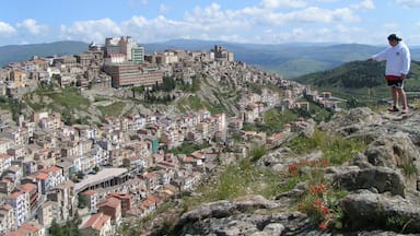 Uma cidade montanhosa com edifícios históricos e uma pessoa em um afloramento rochoso.