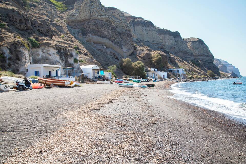 Uma praia de pedras com barcos e edifícios ao longo da costa.