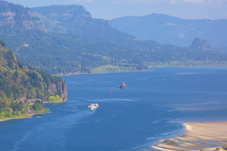 Paisagem costeira com um grande corpo de água, um barco e um litoral rochoso.