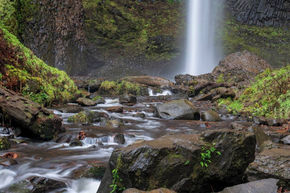 Uma cascata caindo sobre rochas em uma área arborizada.
