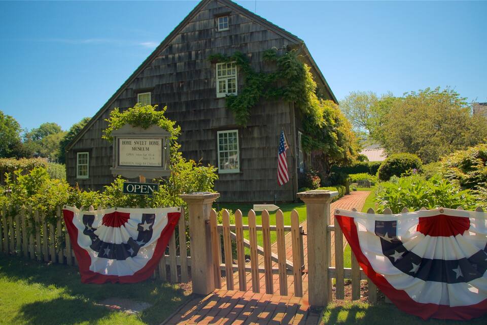 Uma casa de madeira com uma placa que diz 'Home Sweet Home Museum' e uma bandeira americana.