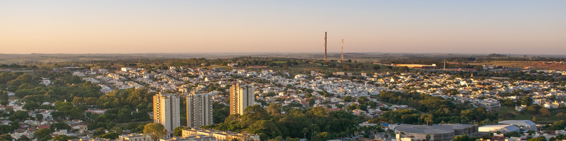 Paisagem urbana com edifícios residenciais, algumas estruturas altas e uma torre de comunicação ao longe.