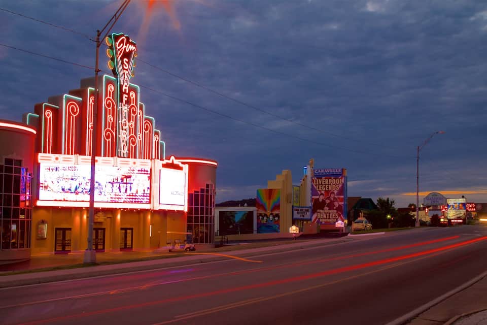 Um teatro iluminado por neon com uma marquise exibindo 'Gumbo Steak' e um cartaz de 'Liverpool Legends'.