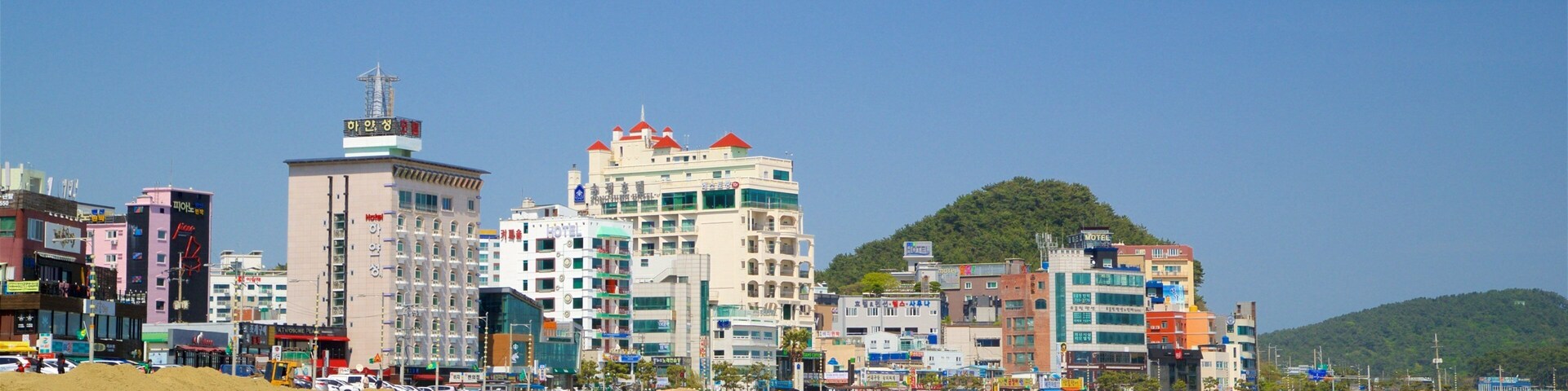 Uma praia com paisagem urbana ao fundo, incluindo hotéis e edifícios.