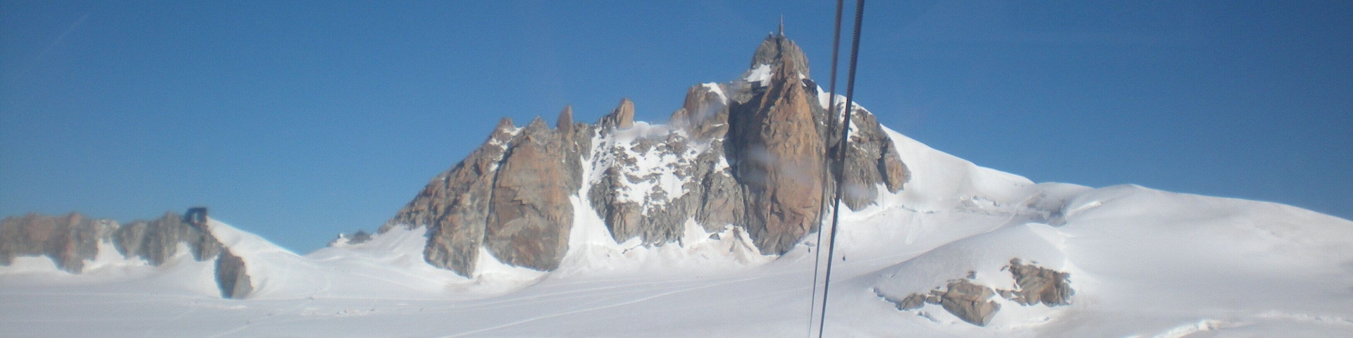 Cordilheira nevada com picos agudos e céu azul límpido.