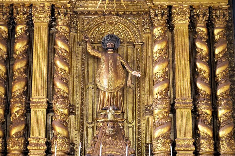 Uma estátua dourada com esculturas detalhadas e colunas.