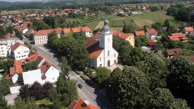 Uma cidade com uma igreja imponente, edifícios com telhados vermelhos e campos verdes ao redor.