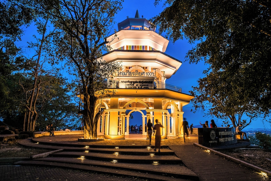 Um pagode de vários níveis com arcos iluminados e uma placa escrita em caracteres estrangeiros.