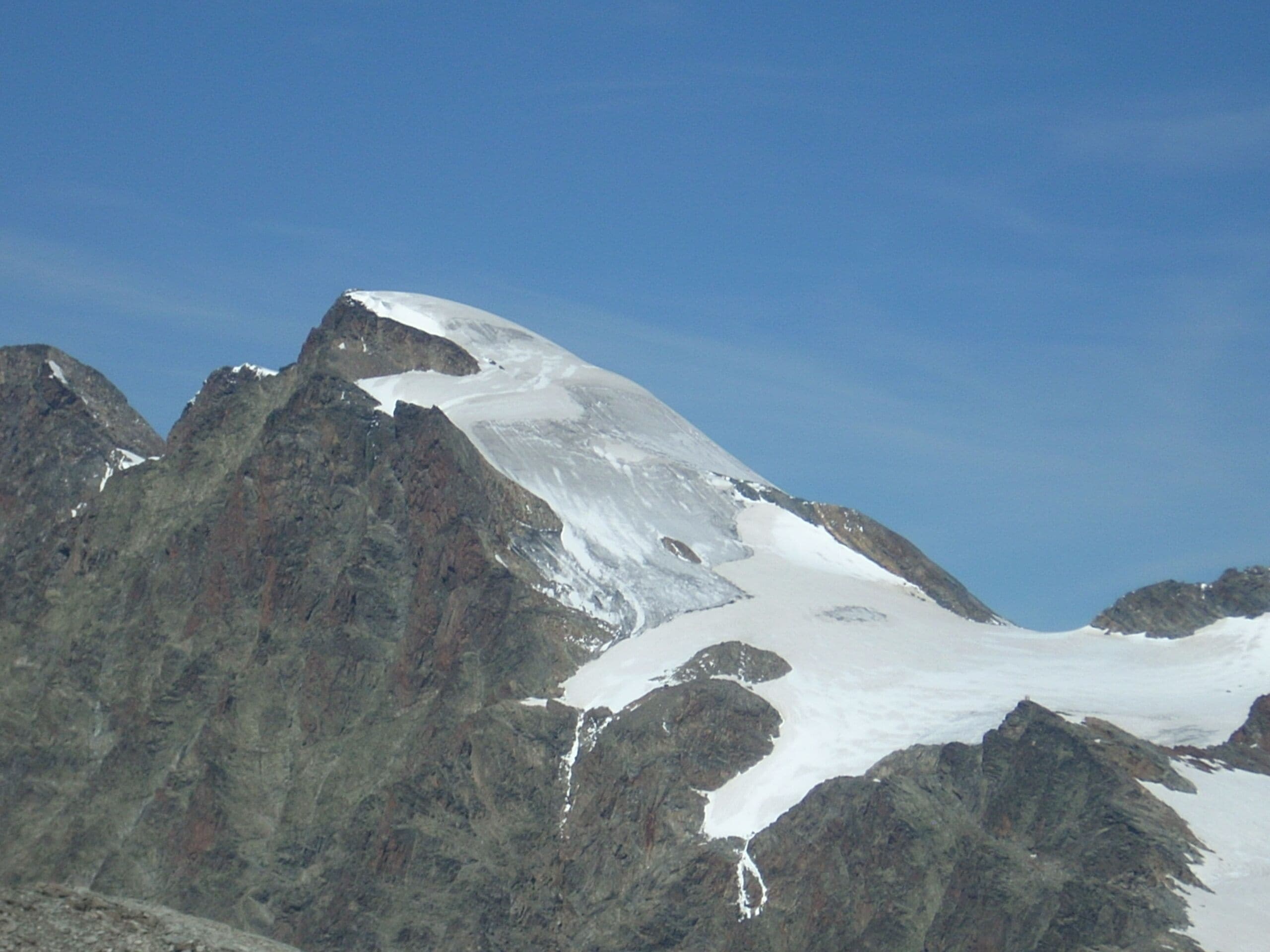 Montanha nevada com terreno acidentado e geleira.