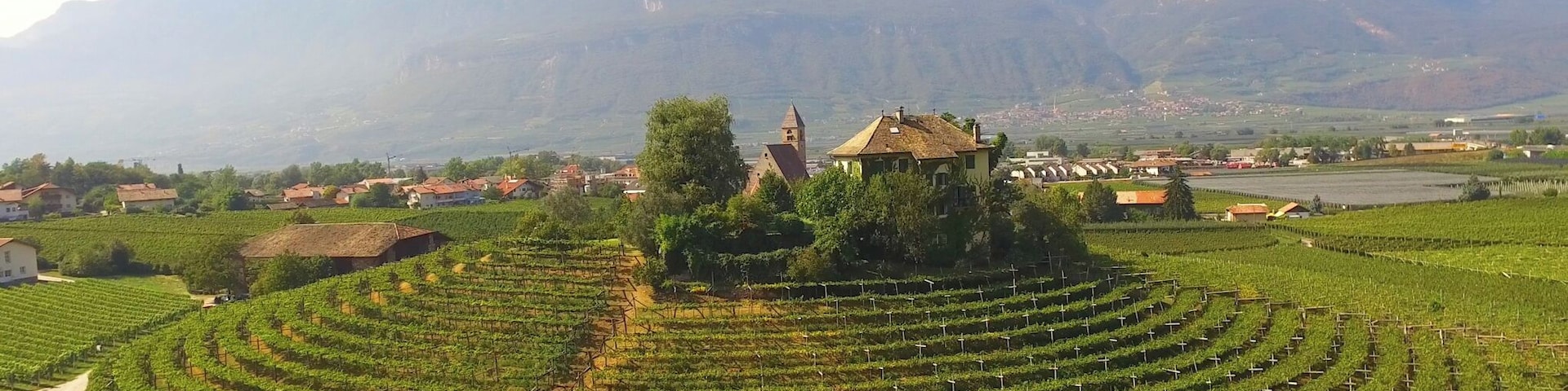 Das Villnerschlössl bzw. Viller Schlössl im Weingut Baron Longo in Neumarkt an der Etsch in Südtirol mit der Villner Kirche im Hintergrund.