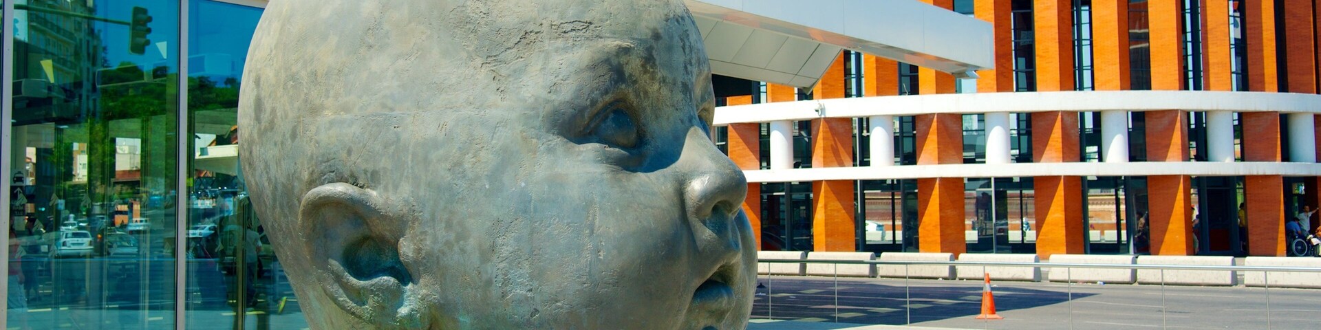 Uma grande escultura de bronze de uma cabeça humana em uma praça pública.