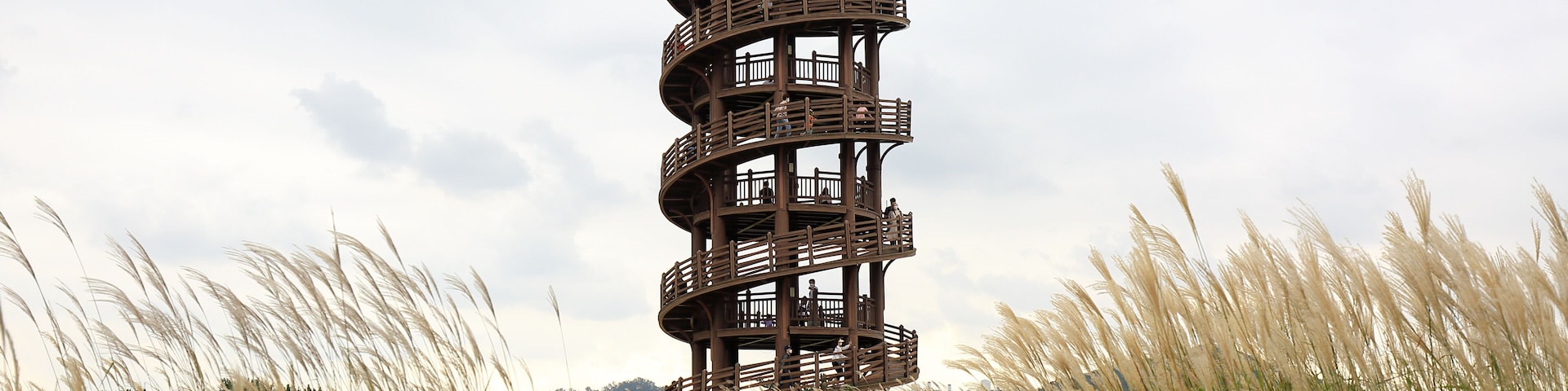 Uma estrutura de torre em espiral, cercada por grama alta e um caminho estreito que a leva.
