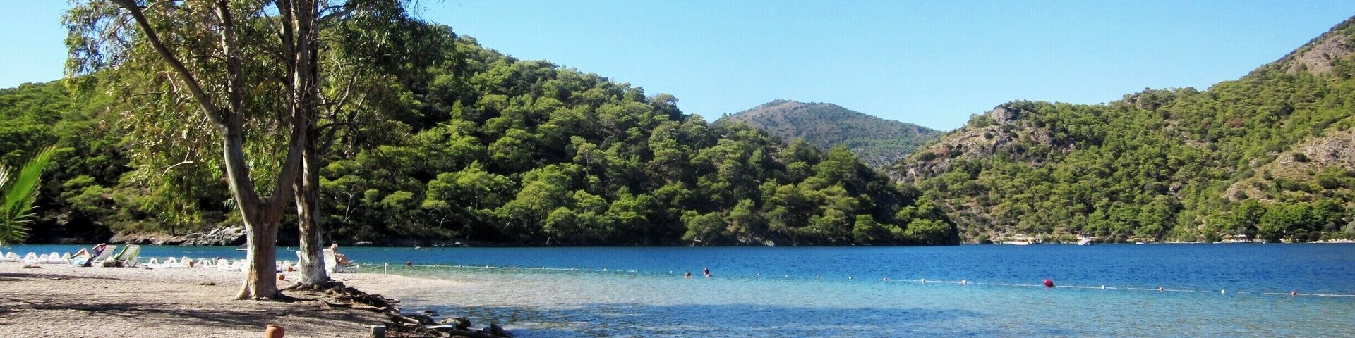 Um lago límpido rodeado por colinas e árvores.