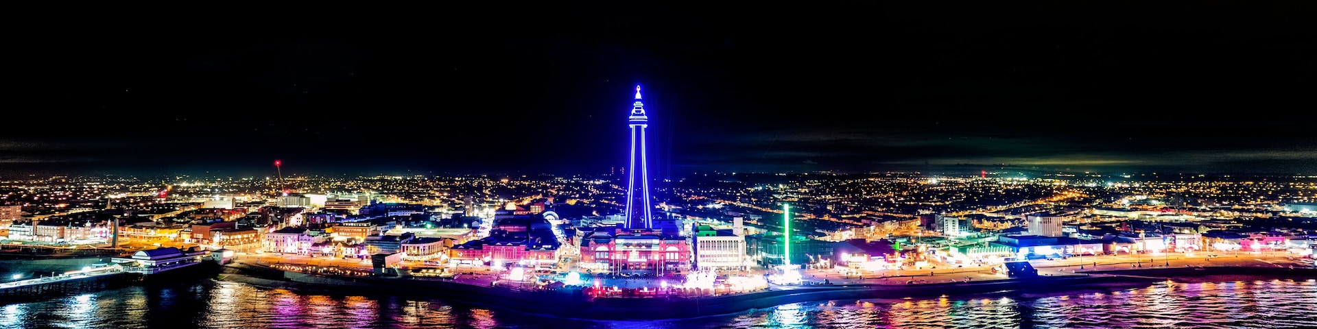 Paisagem urbana noturna com uma torre imponente e área costeira.