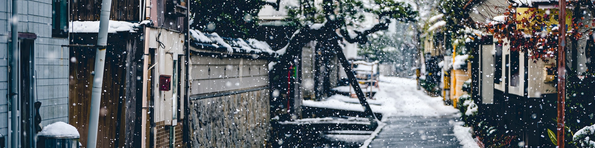 Rua coberta de neve, com casas e calçada.